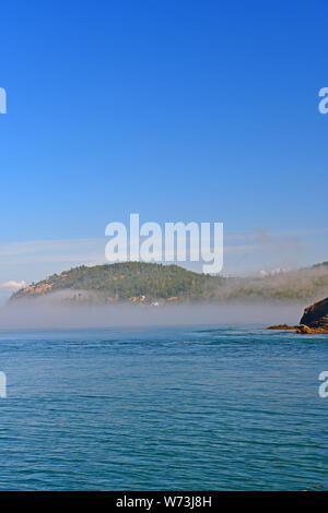 Morning fog hugs the coastline of Deception Pass near the San Juan ...