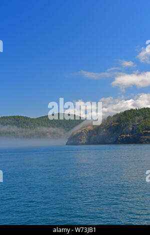 Morning fog hugs the coastline of Deception Pass near the San Juan ...