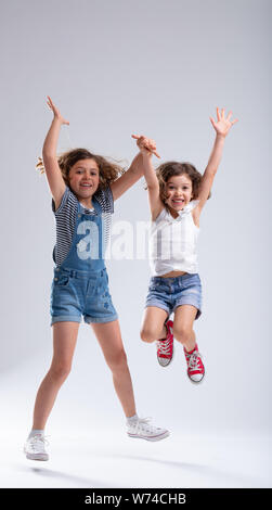 Two exuberant hyperactive young girls jumping Stock Photo - Alamy