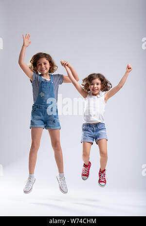 Two vivacious lively little girls jumping together Stock Photo - Alamy