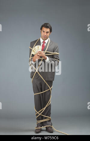 Businessman tied up with a rope struggle to get free Stock Photo - Alamy