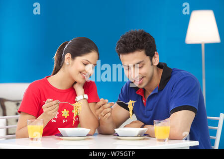 Young couple eating noodles at breakfast table Stock Photo - Alamy