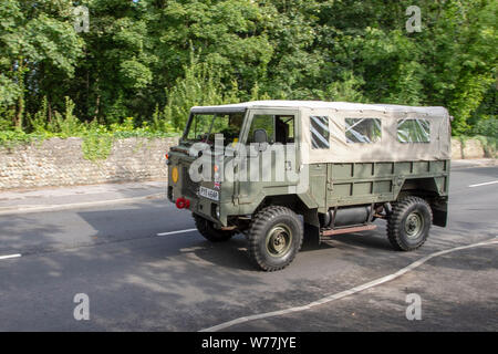 An old British military Land Rover rots in a hedgerow parked next to ...