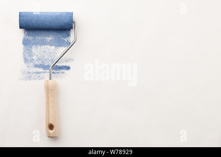 Roller with blue paint on wallpaper background Stock Photo - Alamy