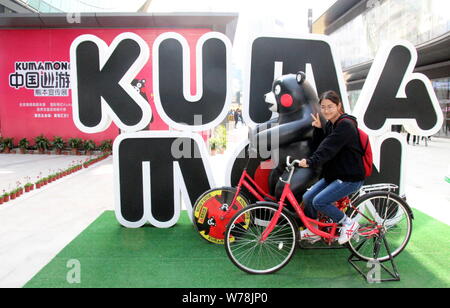 A visitor poses with a Kumamon sculpture for photos at the exhibition ...