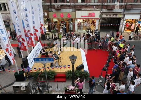 Chinese vistiors look at a French brand performing at the street market ...