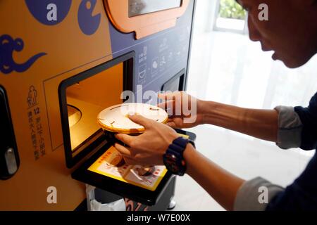 A customer gets his noodles from a mobile self-service noodle vending ...