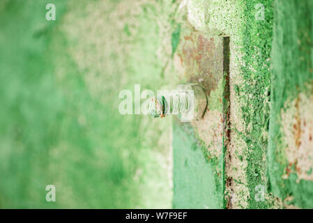 Old painted bolt and nut in a concrete green wall. metal mount to the ...