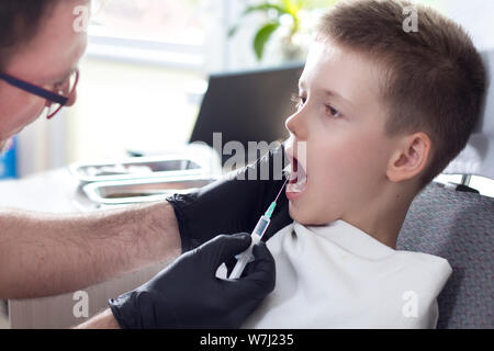 Injection of anesthesia, boy in dental chair, pediatric dentistry ...