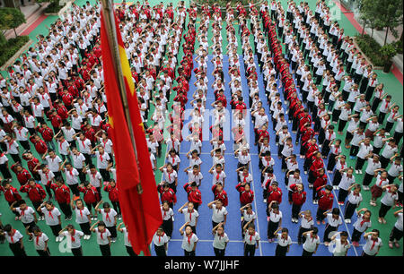 Chinese students salute during a flag-raising ceremony on the first day ...