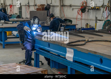 Chinese factory work welds stainless steel parts at a factory near ...