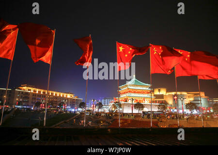 Chinese national flags flutter at night outside the Xi'an Bell Tower ...