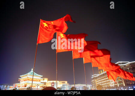 Chinese national flags flutter at night outside the Xi'an Bell Tower ...