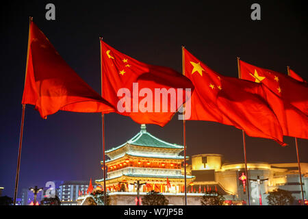 Chinese national flags flutter at night outside the Xi'an Bell Tower ...