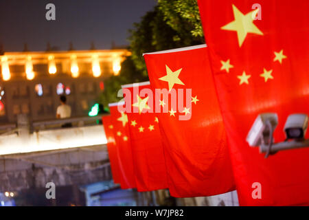 Chinese national flags flutter at night outside the Xi'an Bell Tower ...
