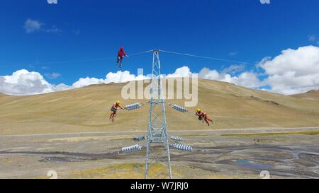 Chinese workers labor at the world's highest power transmission tower lines with a height of ...