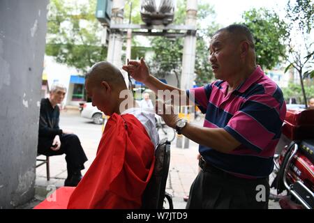 A customer gets his hair cut by the 62-year-old Chinese barber Xiong ...