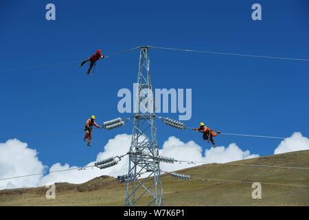 Chinese workers labor at the world's highest power transmission tower lines with a height of ...