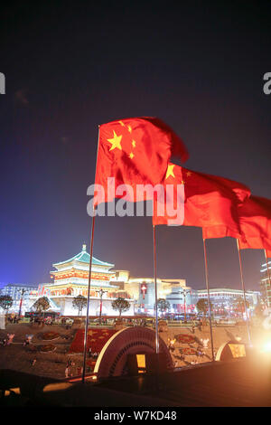 Chinese national flags flutter at night outside the Xi'an Bell Tower ...