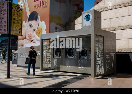 A pedestrian walks past public washing machines installed outside a ...