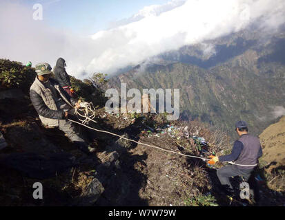 Chinese workers clean up the garbage left by tourists on a beach at the ...