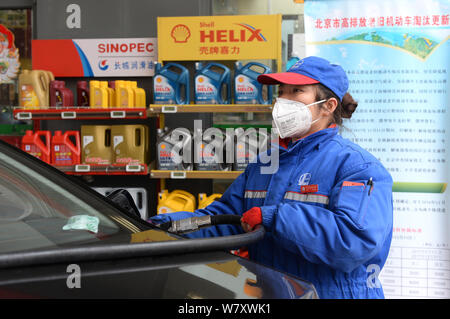 A Chinese worker refuels a car at a gas station in Luoyang city ...