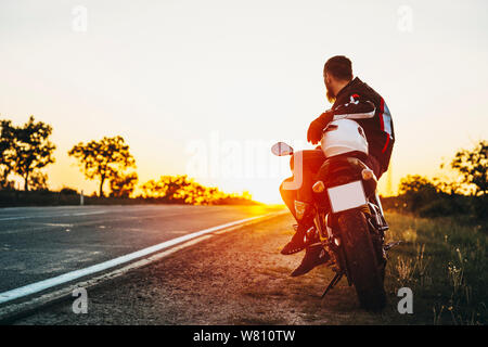 Back view of bearded male biker looks thoughtfully somewhere into ...