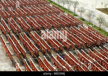 Chinese workers hang Jinhua hams to dry them in the sun in a factory of ...
