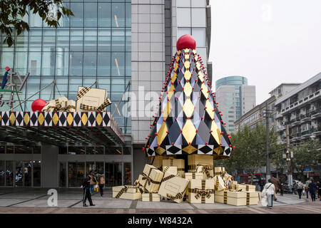 A giant Christmas tree with golden decorations is displayed outside a ...