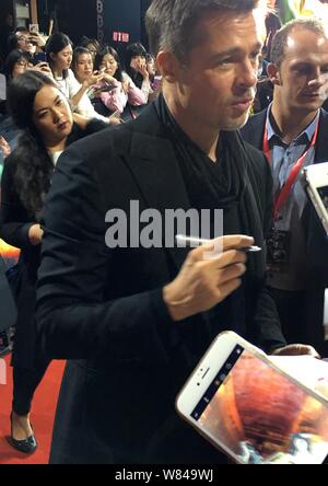 Brad Pitt signs autographs as he arrives for the premiere of the film ...
