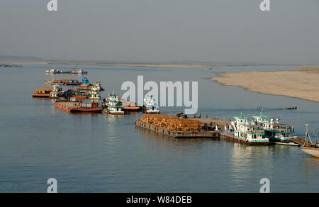 On the Irrawady River, countless barges carrying wood, come docking to ...