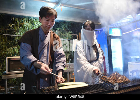 Chinese waiter and waitress wearing ancient Chinese costumes barbecue ...
