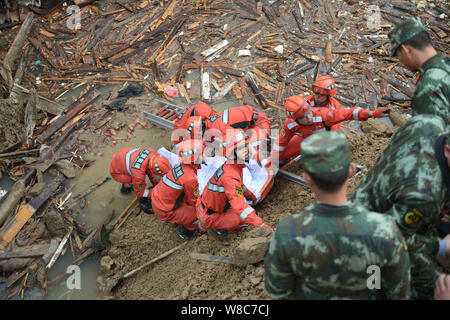 Rescuers carry the body of a victim at a village hit by a flood in ...
