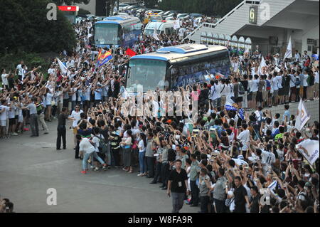 A crowd of football fans watch the arrival of a bus carrying players of ...
