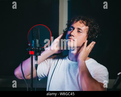 Male vocal artist with curly hair singing alone.Singer man writing song ...
