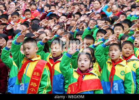 Chinese students salute during a flag-raising ceremony on the first day ...