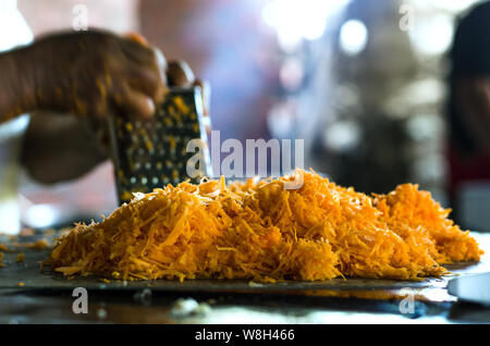 Hands of a woman scratching the carrot, with a metal grater in hand ...