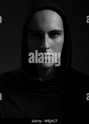 Mysterious angry man in black hoodie with hood on the head on dark ...