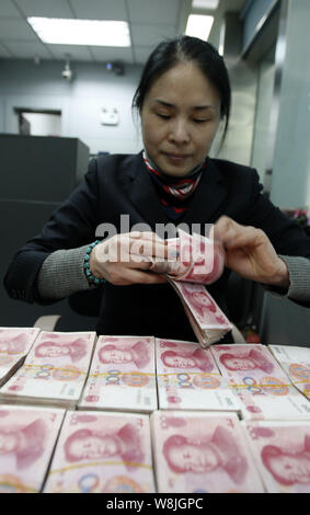 --FILE--A bank clerk counts RMB Yuan banknotes at a bank in Nantong ...