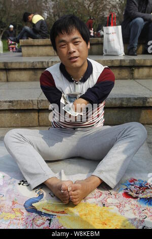 Armless Chinese man Xiaolou shows money received from pedestrians as he ...