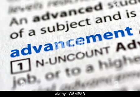 The word or phrase Advancement in a dictionary highlighted with marker ...