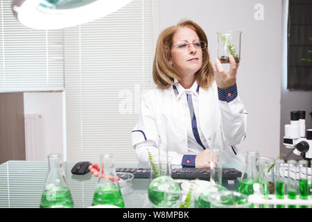 scientist doing research on plants holding a green solution in a test ...