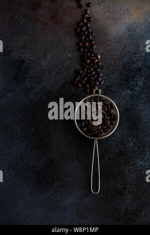 Strained full of coffee beans on dark stone background with copy space ...