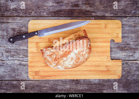 Fresh dark bread in slices. Rustic wooden cutting board and table ...