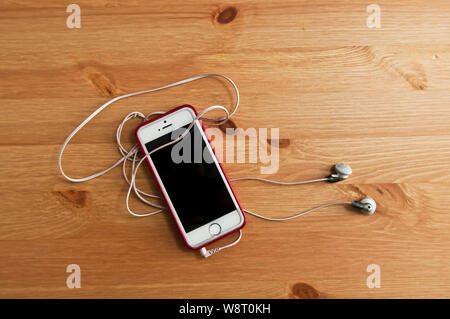 top down view of an iPhone and earpiece lying on a table Stock Photo ...