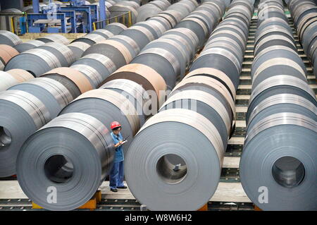 --FILE--A Chinese worker checks rolls of coiled steel plates at a steel ...