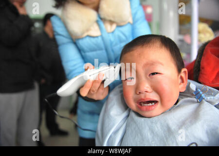 A Chinese kid has his hair cut at the barbers on Dragon Heads-raising ...