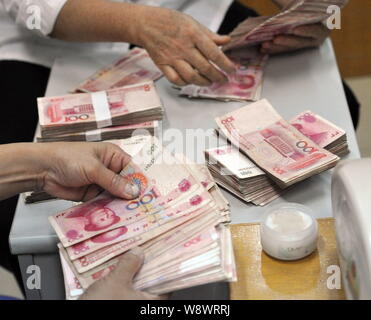 Chinese clerks count RMB (renminbi) yuan banknotes at a bank in Haian ...