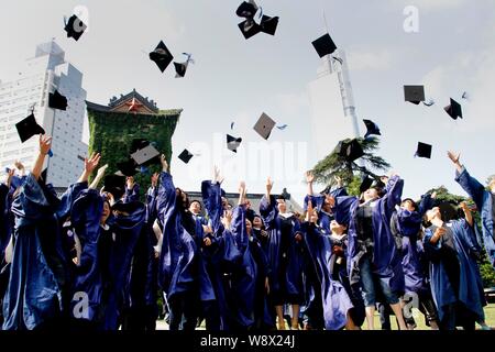 Chinese graduates dressed in academic gowns throw hats into the air to ...