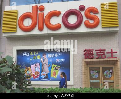 A pedestrian walks past a Dicos fastfood restaurant in Chongqing, China ...